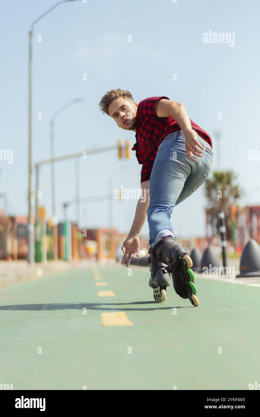 A young man engages in inline skating on a city bike lane, performing ...
