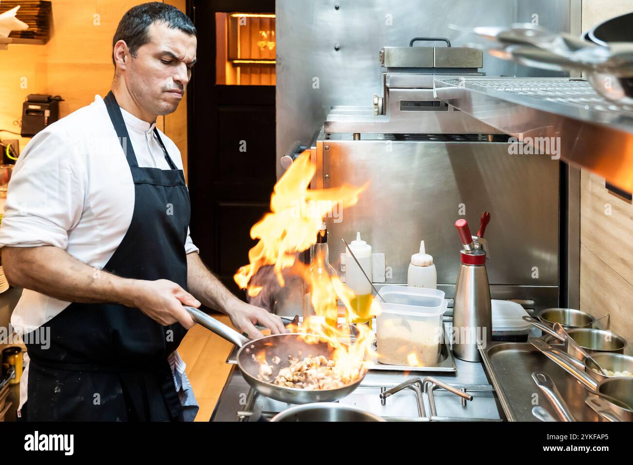 In the kitchen of a professional restaurant, a chef deftly handles a ...