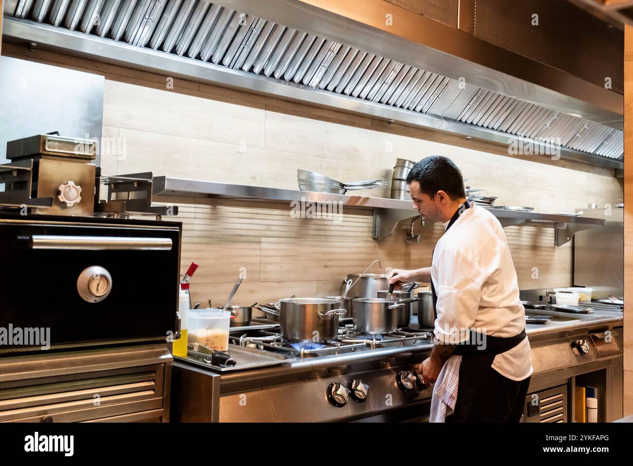 A focused chef meticulously prepares multiple dishes in a bustling ...