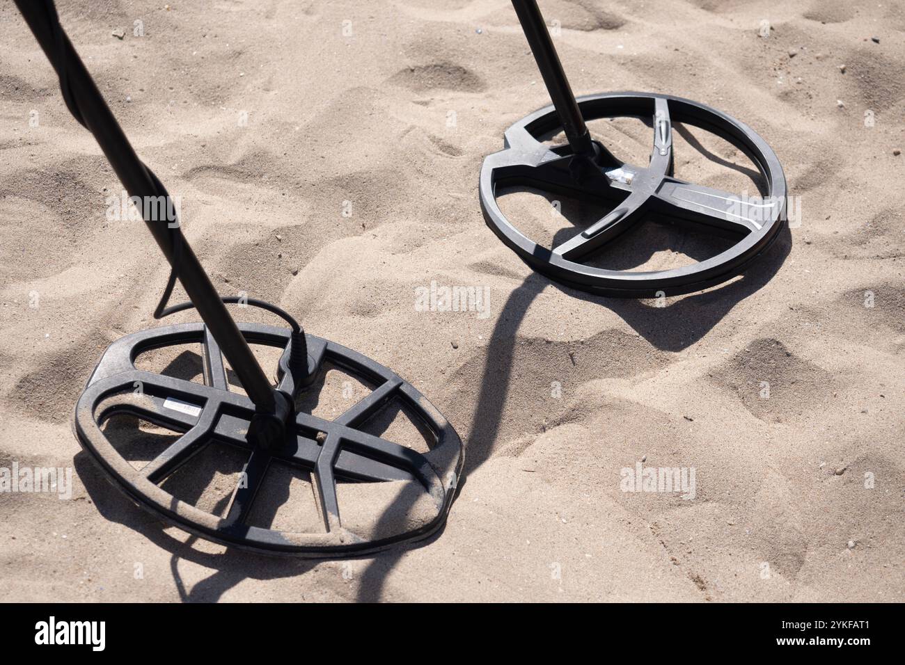 Two metal detectors are plunged into the sandy beach environment ...