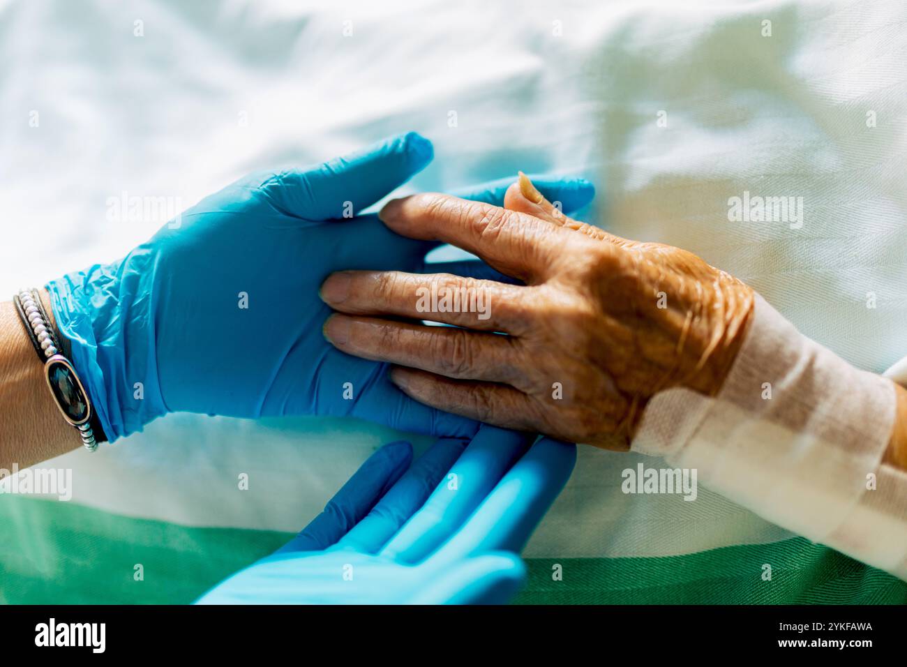 A senior woman in a hospital bed receives comfort from a nurse wearing ...