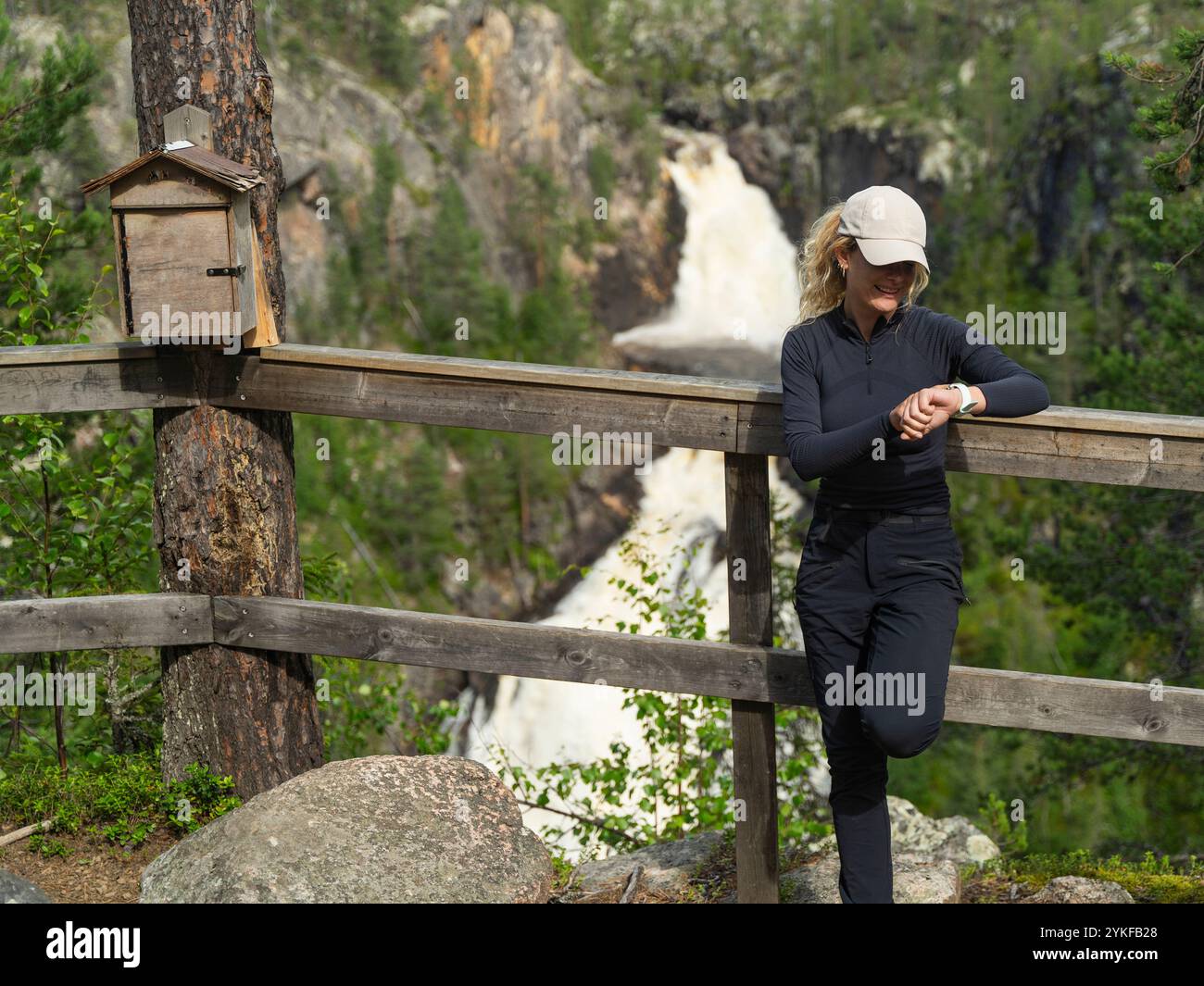 A woman smiles joyfully while checking the time on her watch, taking a ...