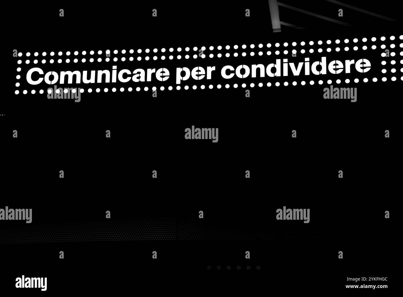 lettering: communicate to share, in white backlit on a black background ...