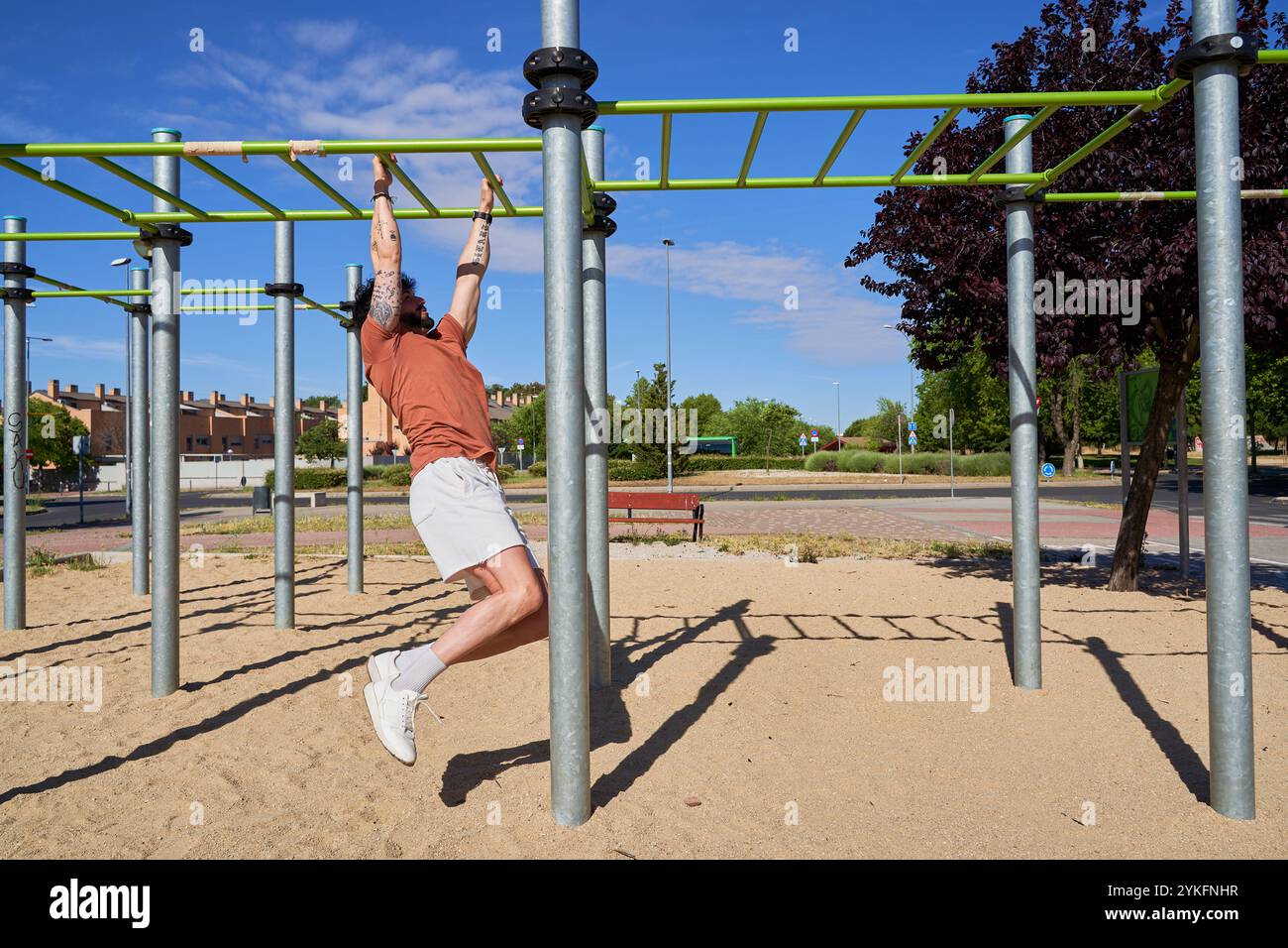 A young athlete performs pull-ups at an outdoor calisthenics park ...