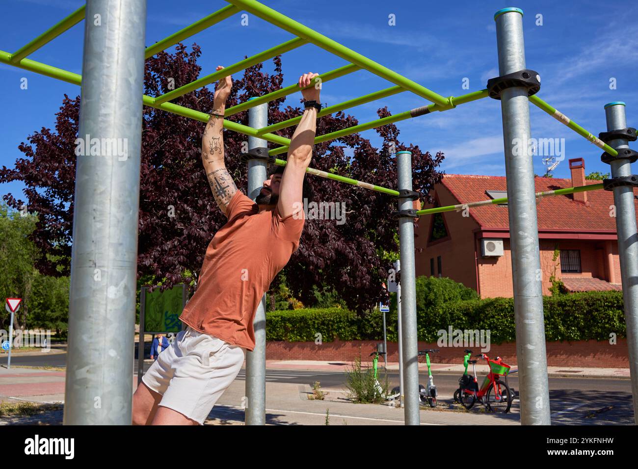A young athlete performs pull-ups at an outdoor calisthenics park ...
