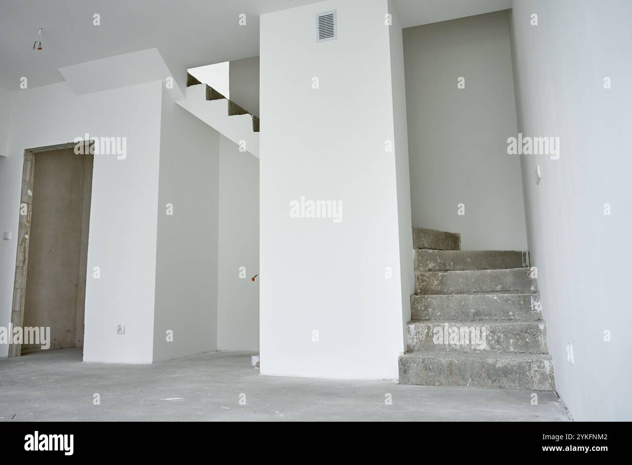 Empty apartment with unfinished concrete staircase and white walls ...