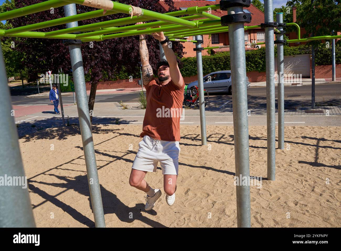 A young athlete performs pull-ups at an outdoor calisthenics park ...