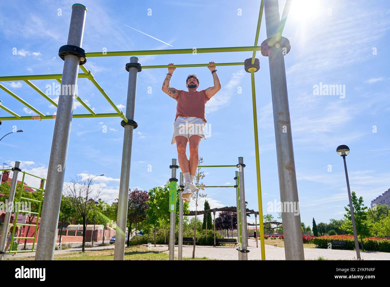 A young athlete performs pull-ups at an outdoor calisthenics park ...