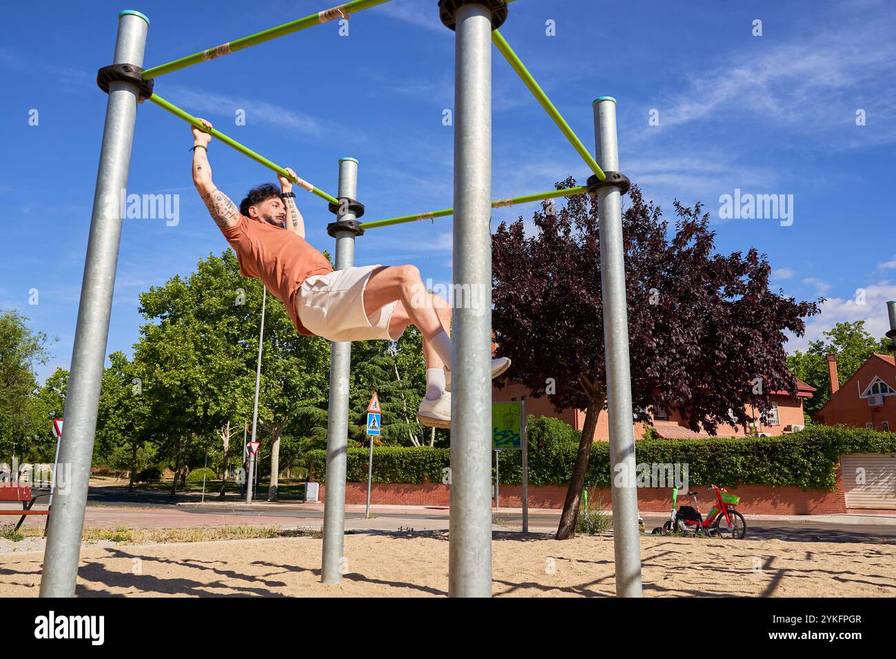 A young athlete performs pull-ups at an outdoor calisthenics park ...