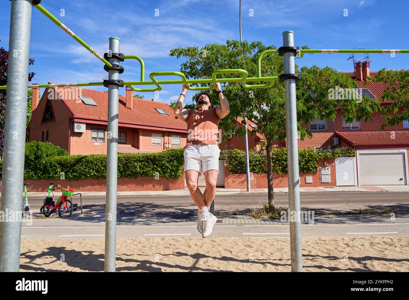 A young athlete performs pull-ups at an outdoor calisthenics park ...