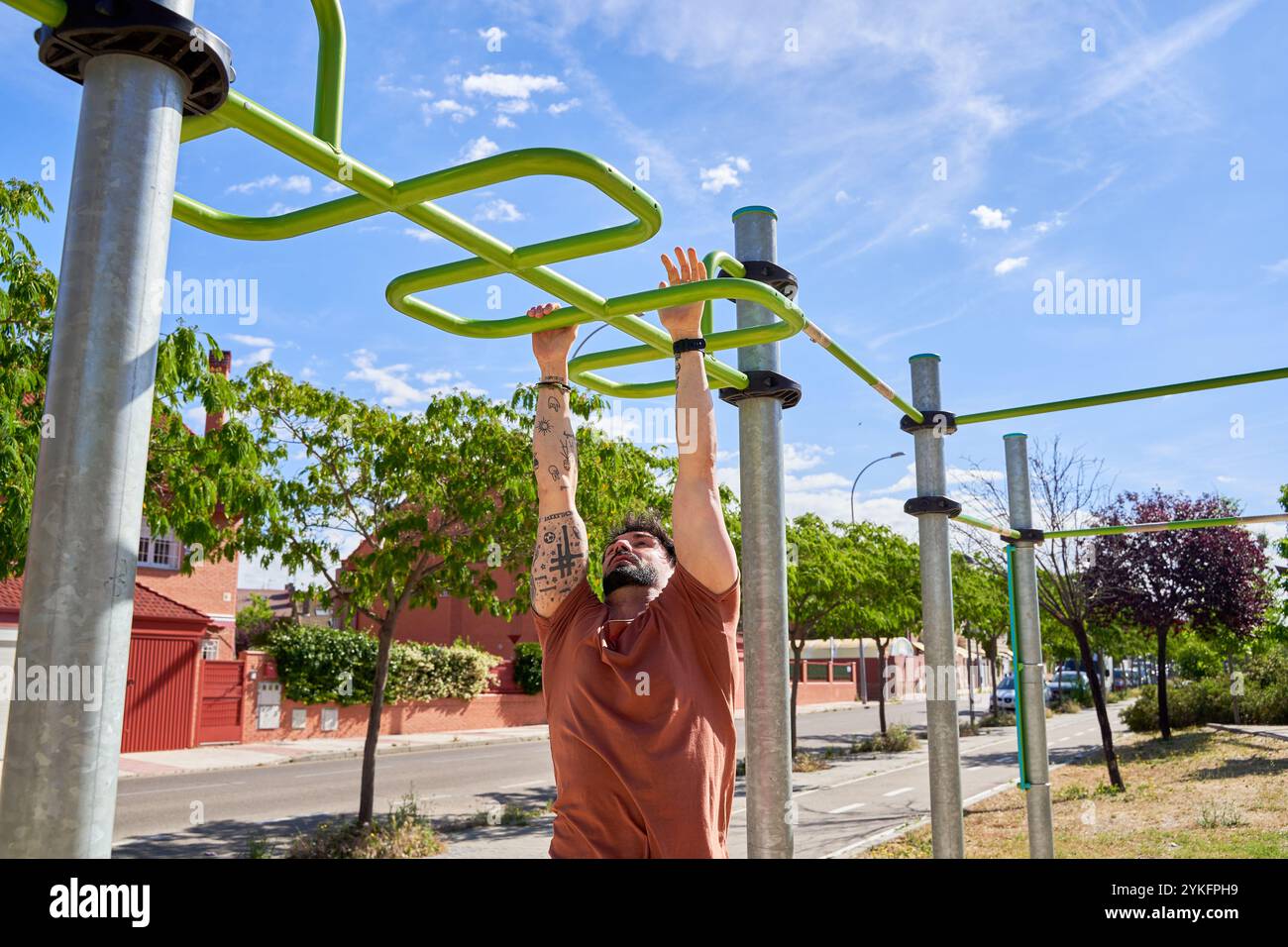 A young athlete performs pull-ups at an outdoor calisthenics park ...