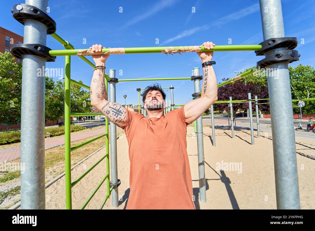 A young athlete performs pull-ups at an outdoor calisthenics park ...