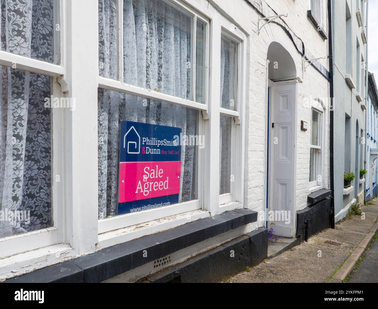 An estate agent’s Sale Agreed sign in the window of a terraced cottage ...