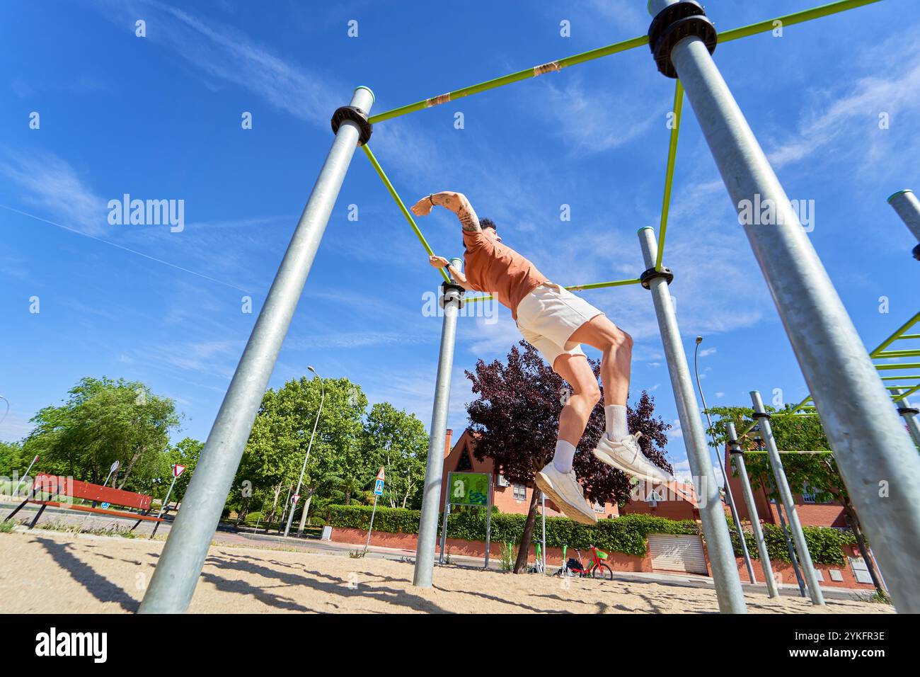 A young athlete performs pull-ups at an outdoor calisthenics park ...