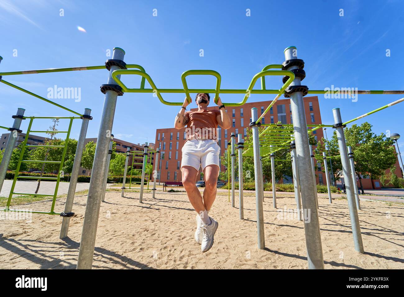 A young athlete performs pull-ups at an outdoor calisthenics park ...