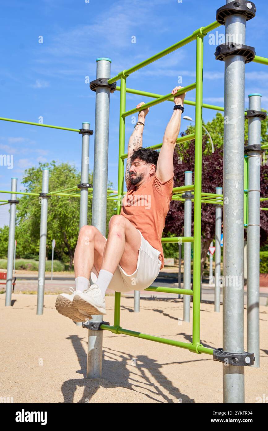 A Caucasian man performs hanging leg raises on a bar, showcasing core ...