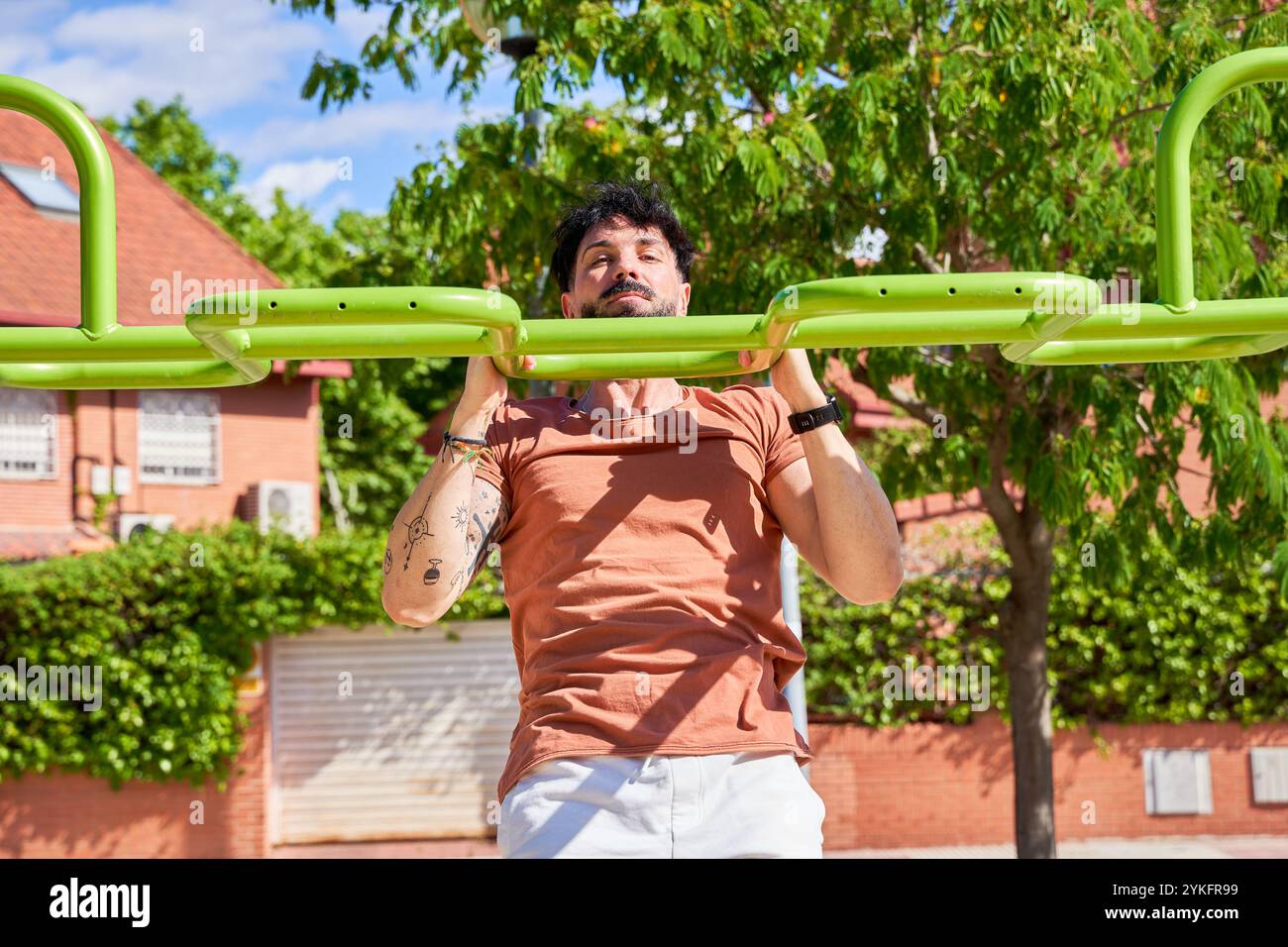 A man engages in a vigorous workout session at an outdoor calisthenics ...