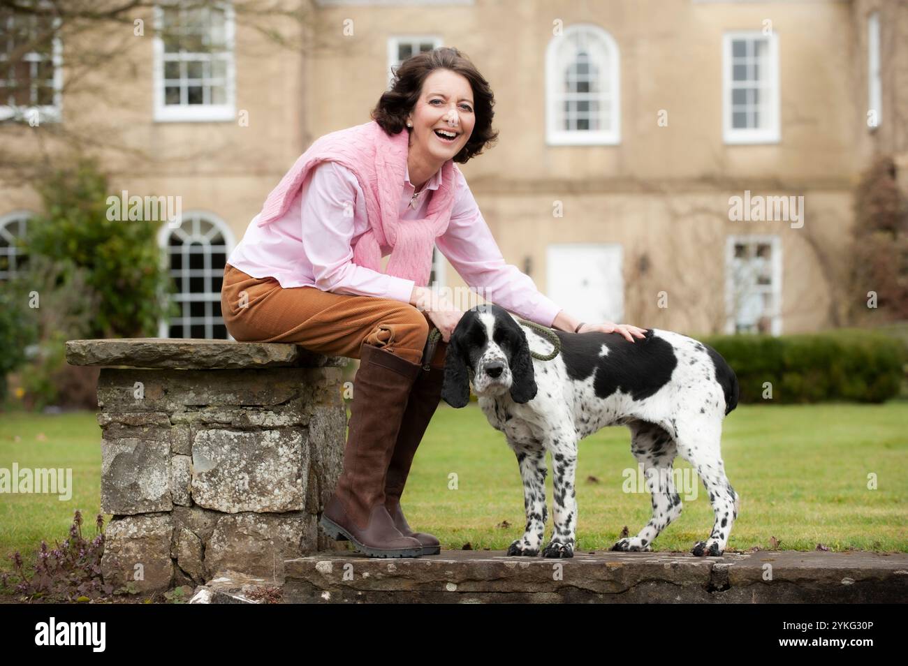 A middle aged woman sat petting her elderly cocker spaniel dog Stock ...