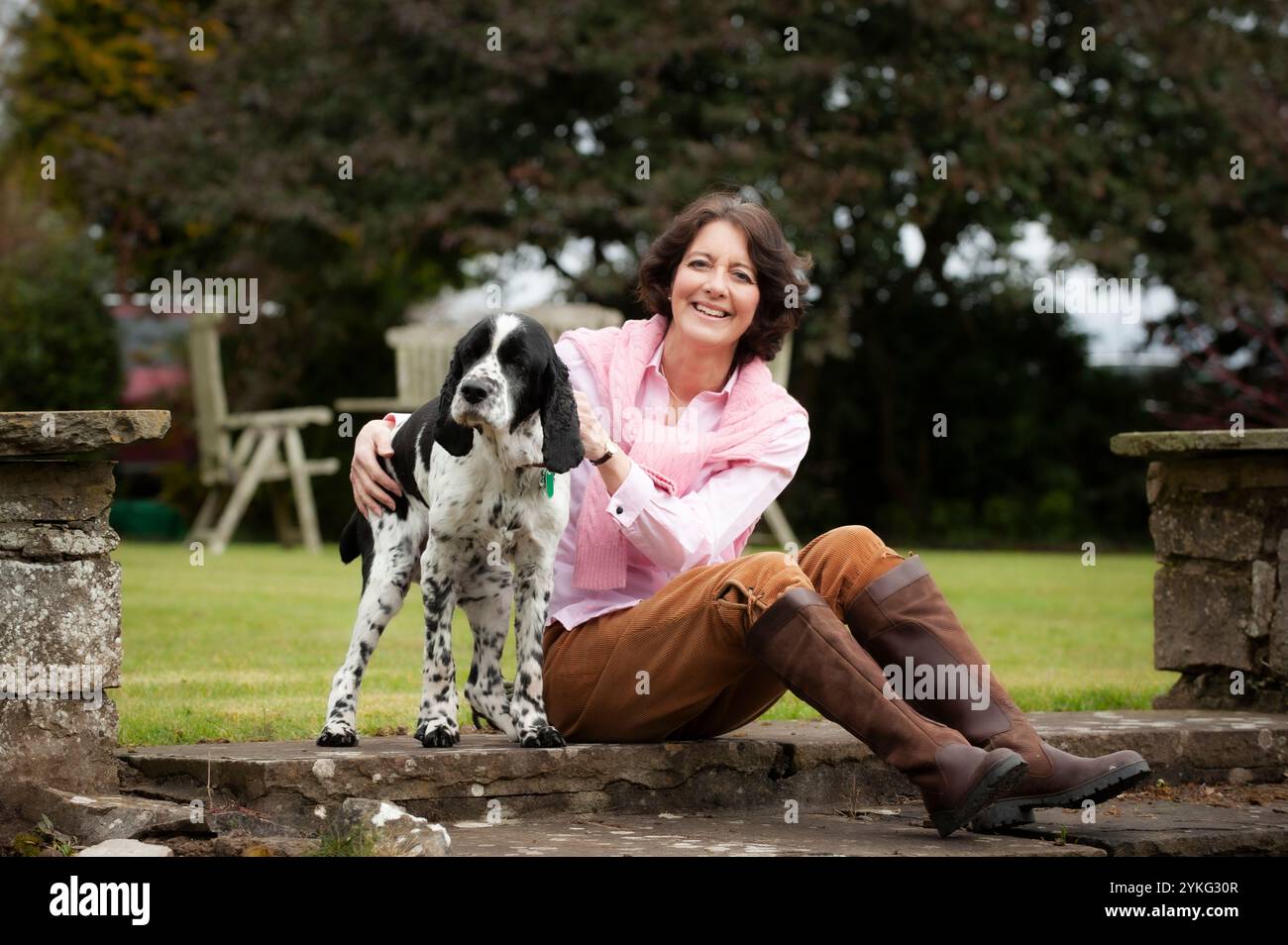 A middle aged woman sat petting her elderly cocker spaniel dog Stock ...