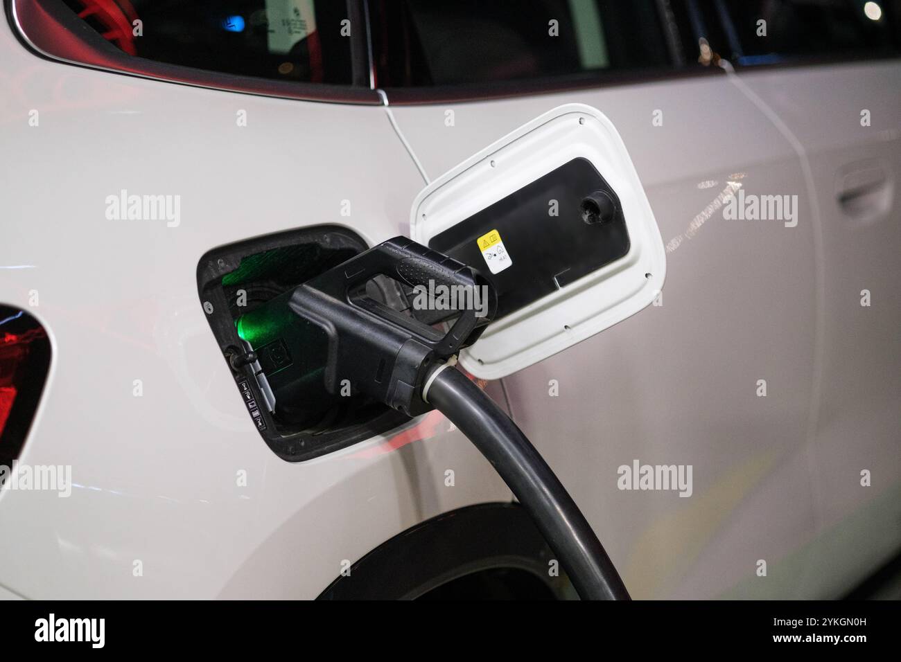 A detailed view of a charging cable plugged into the port of a white ...