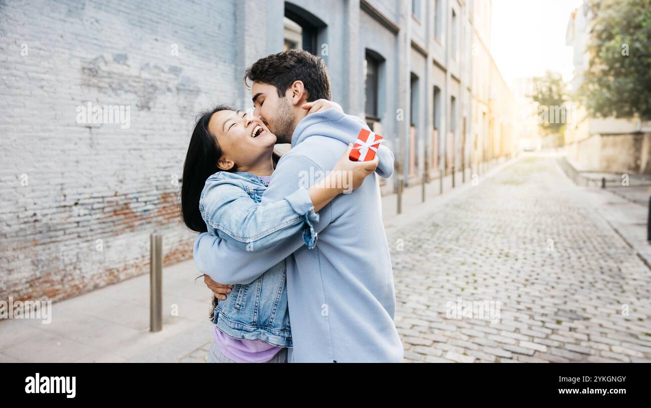 Happy Asian woman embracing her boyfriend after receiving a gift for ...