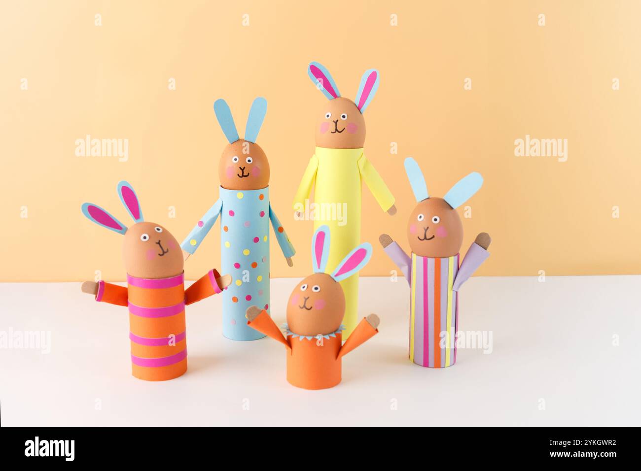 Handmade Easter bunny crafts using colored paper and eggs on a peach ...