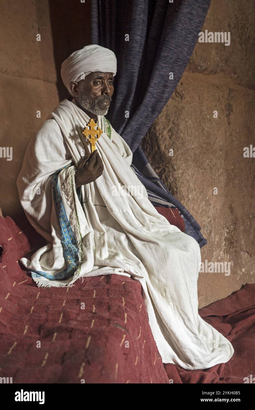 Ethiopian Orthodox priest with a hand cross in the rock church of Biete ...