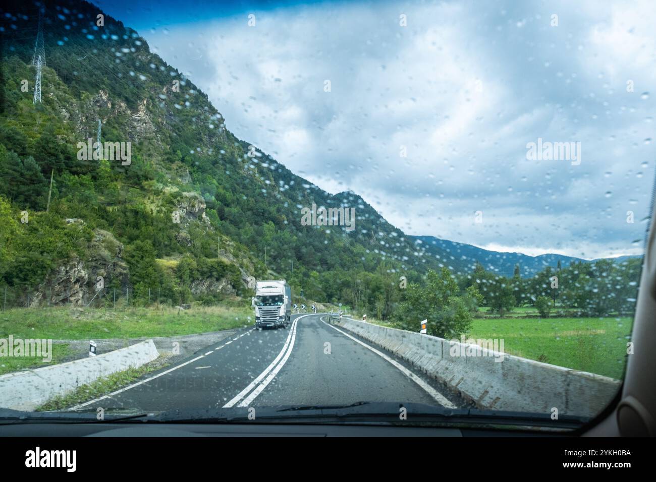 A wet road on a cloudy and rainy day seen from inside a vehicle. There ...
