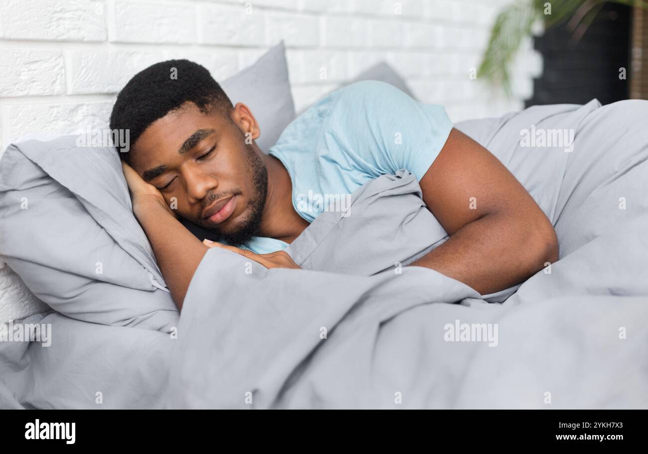 Young african-american man sleeping in bed at home Stock Photo - Alamy