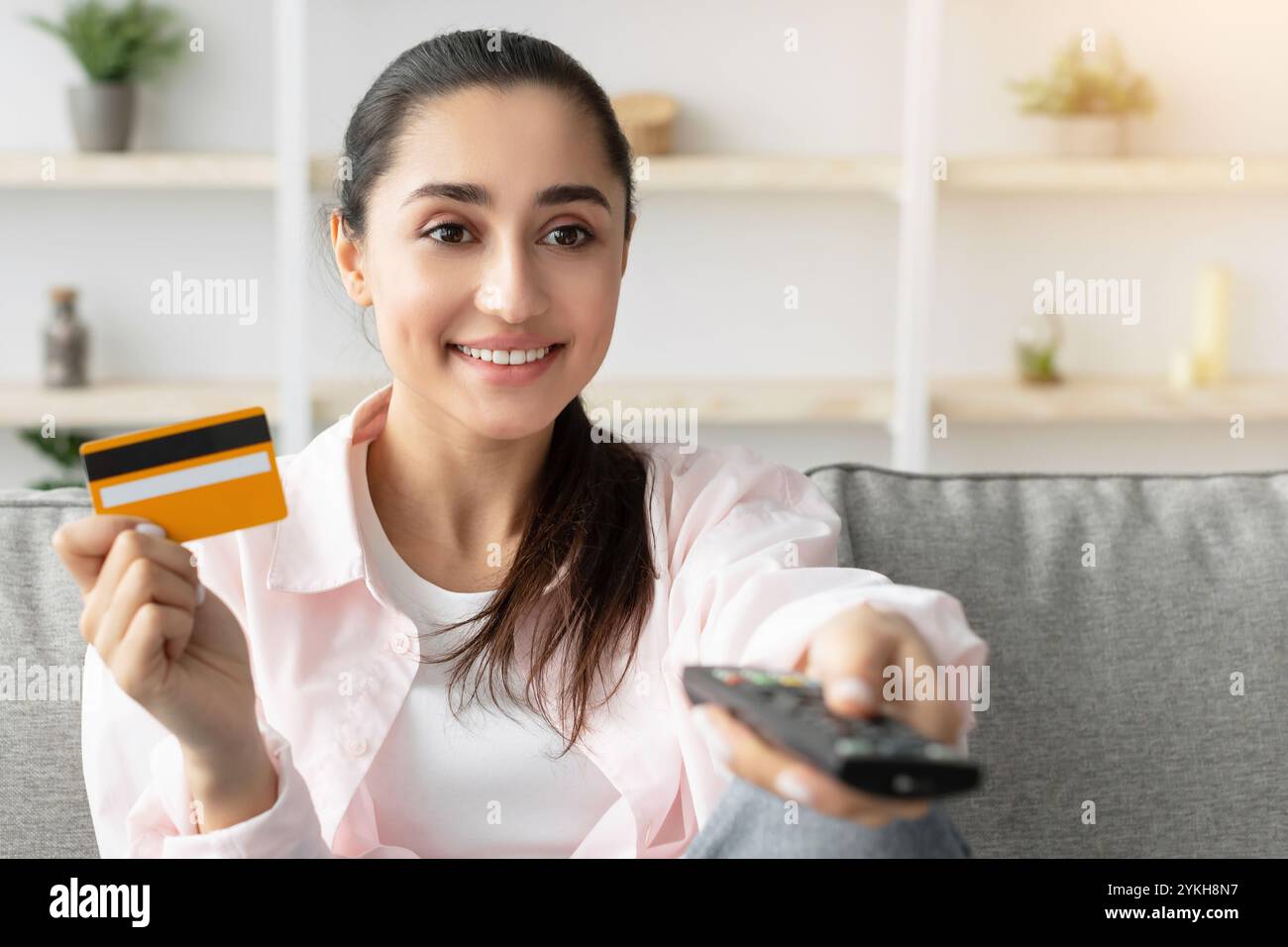 Female relaxing on couch, holding remote control and credit card Stock ...