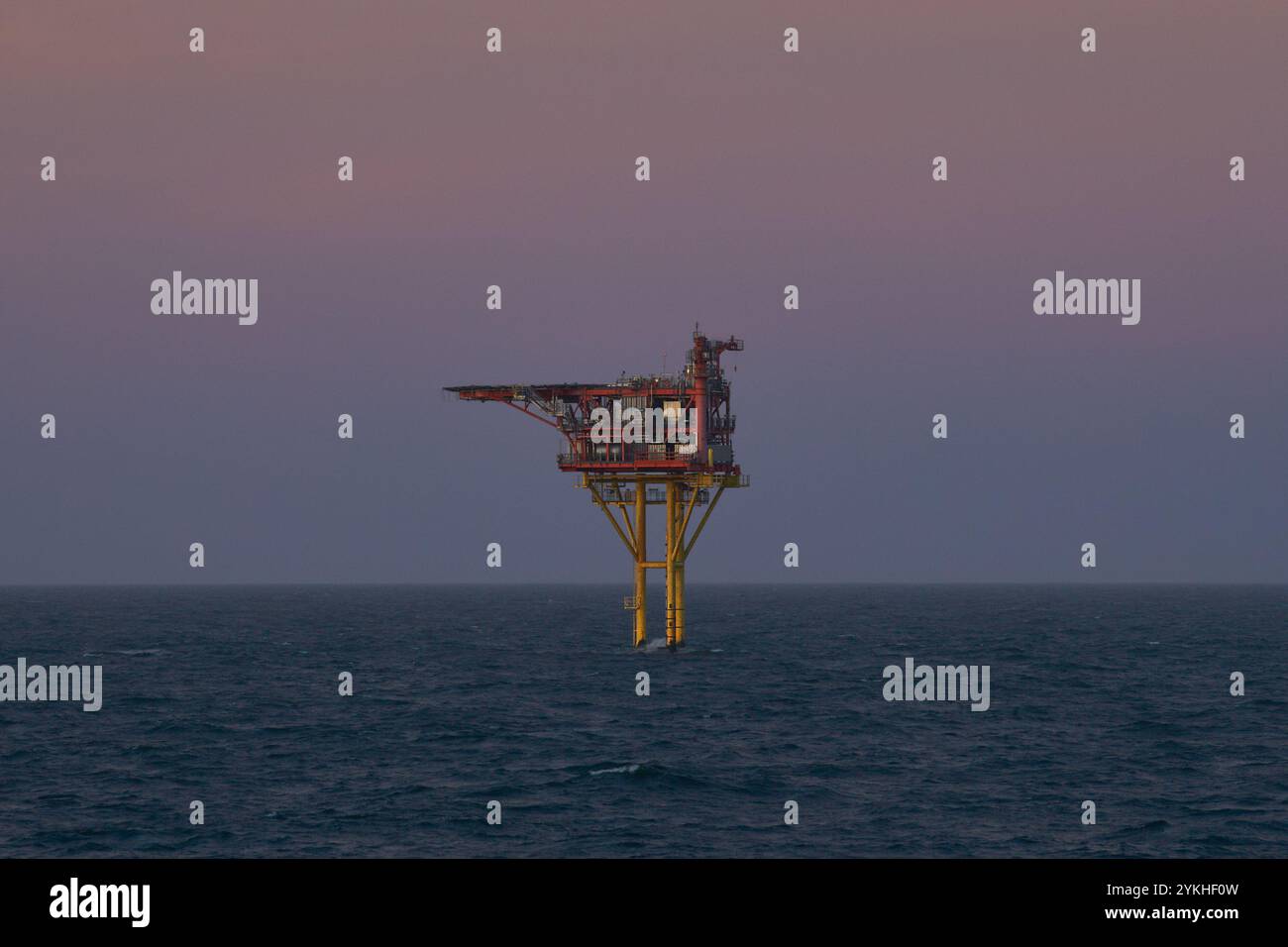 Unmanned offshore oil platform in the sea with colourful sunset sky ...