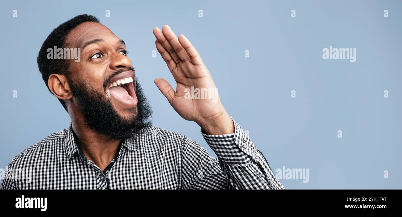 Black guy holding hand near mouth, screaming aside Stock Photo - Alamy