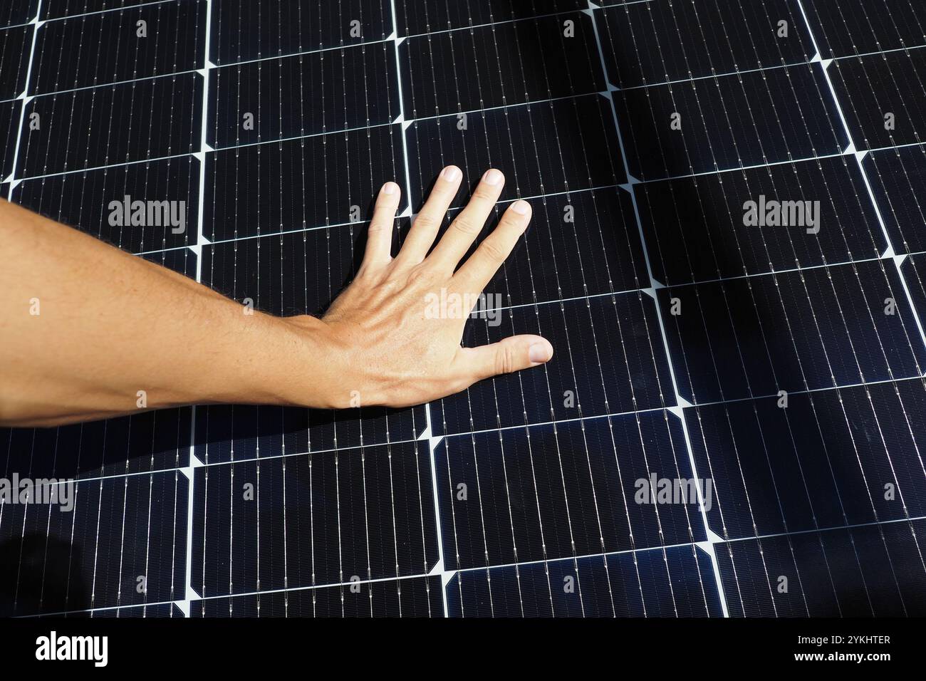 Hand touching solar panel cells in a renewable energy setting during ...