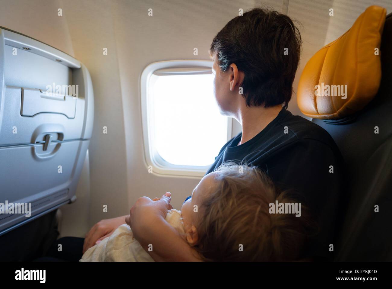 Mother and child looking out airplane window during flight. Concept of ...