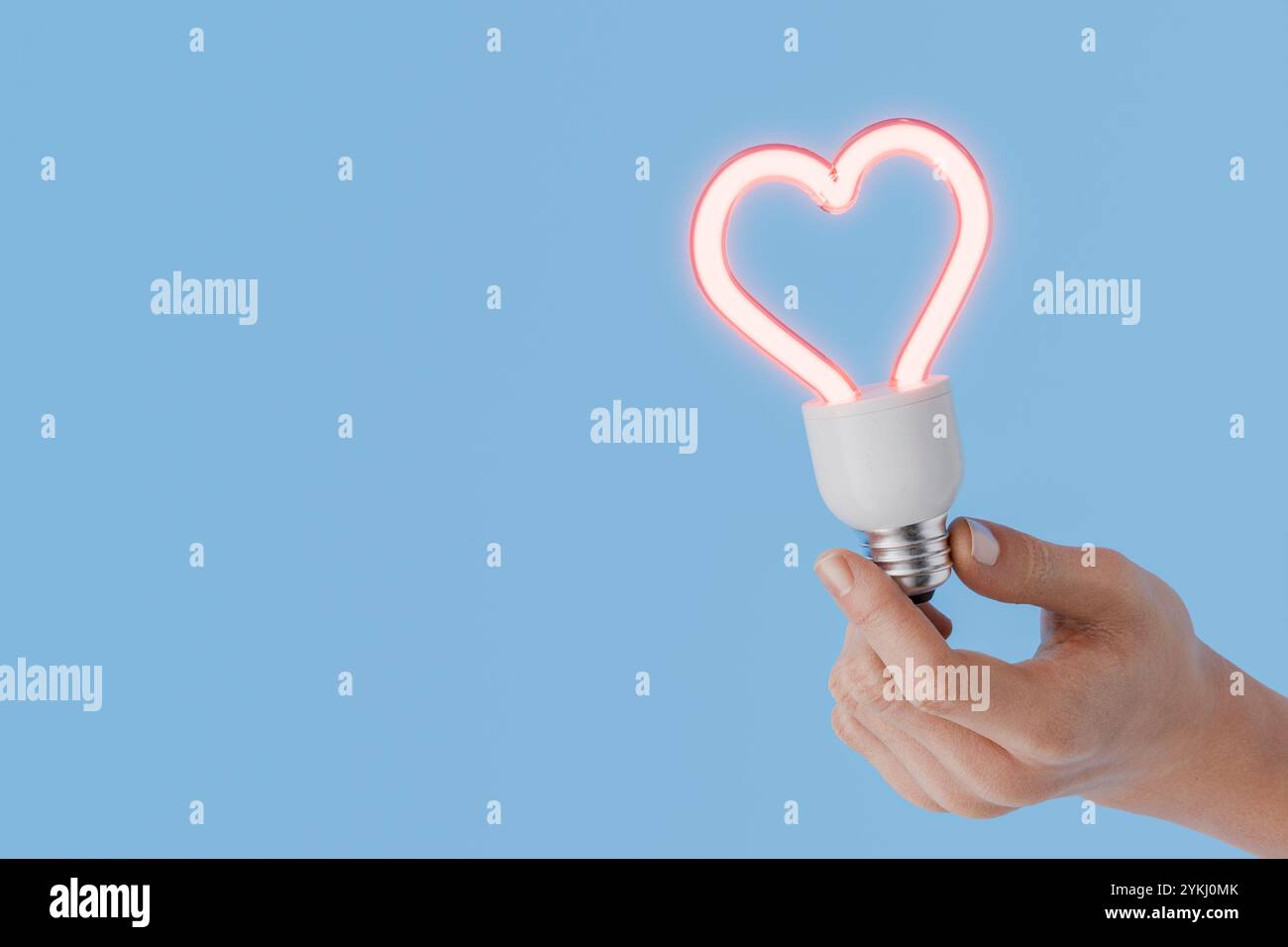 Hand holds a light bulb shaped like a heart, representing the bright ...