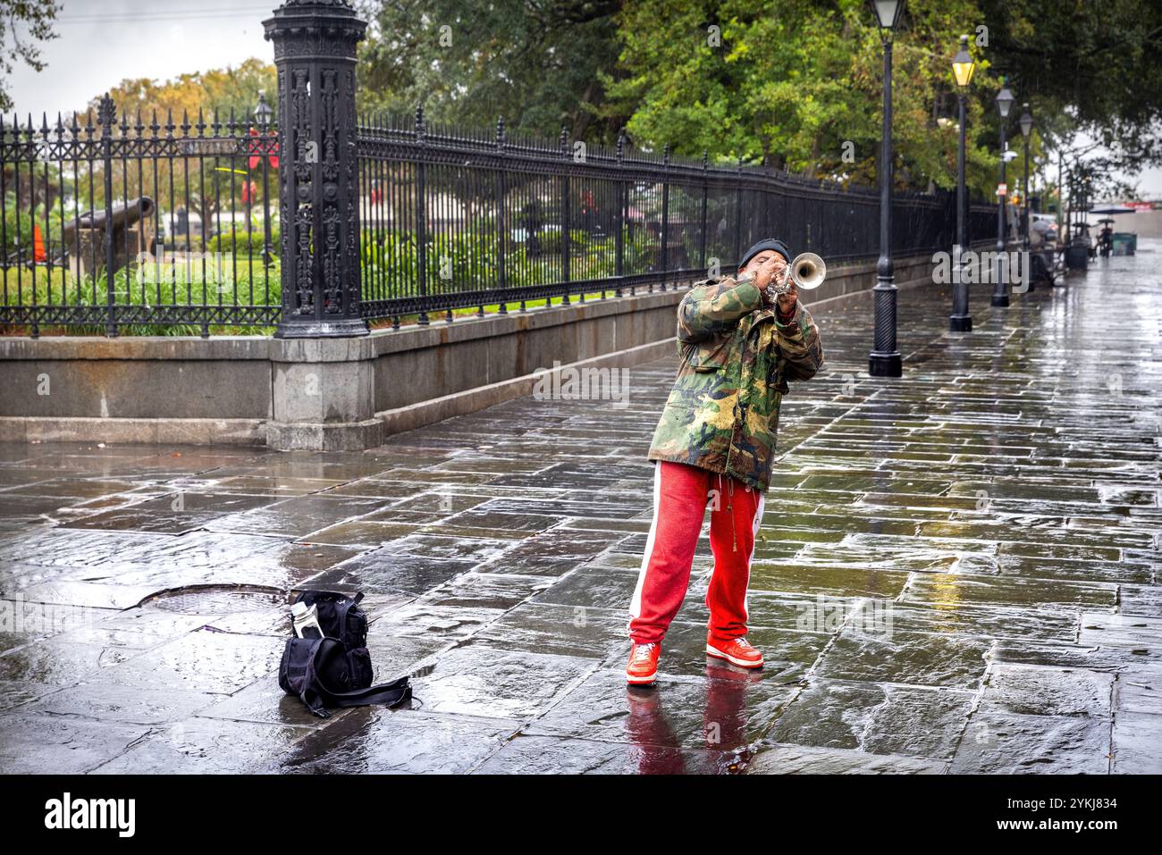 A trumpet player performs in the rain on St. Peter St. next to Jackson ...