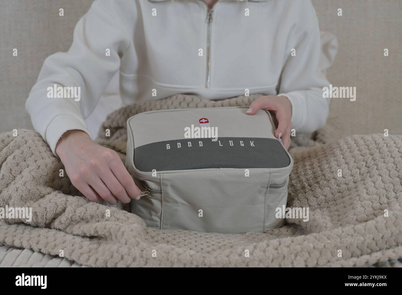Woman holding and opening gray home first aid kit while sitting in bed ...