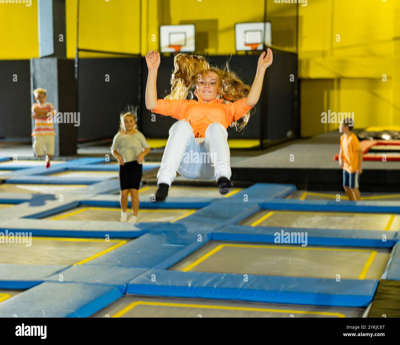 Happy cute little girl jumping on trampoline indoors Stock Photo - Alamy