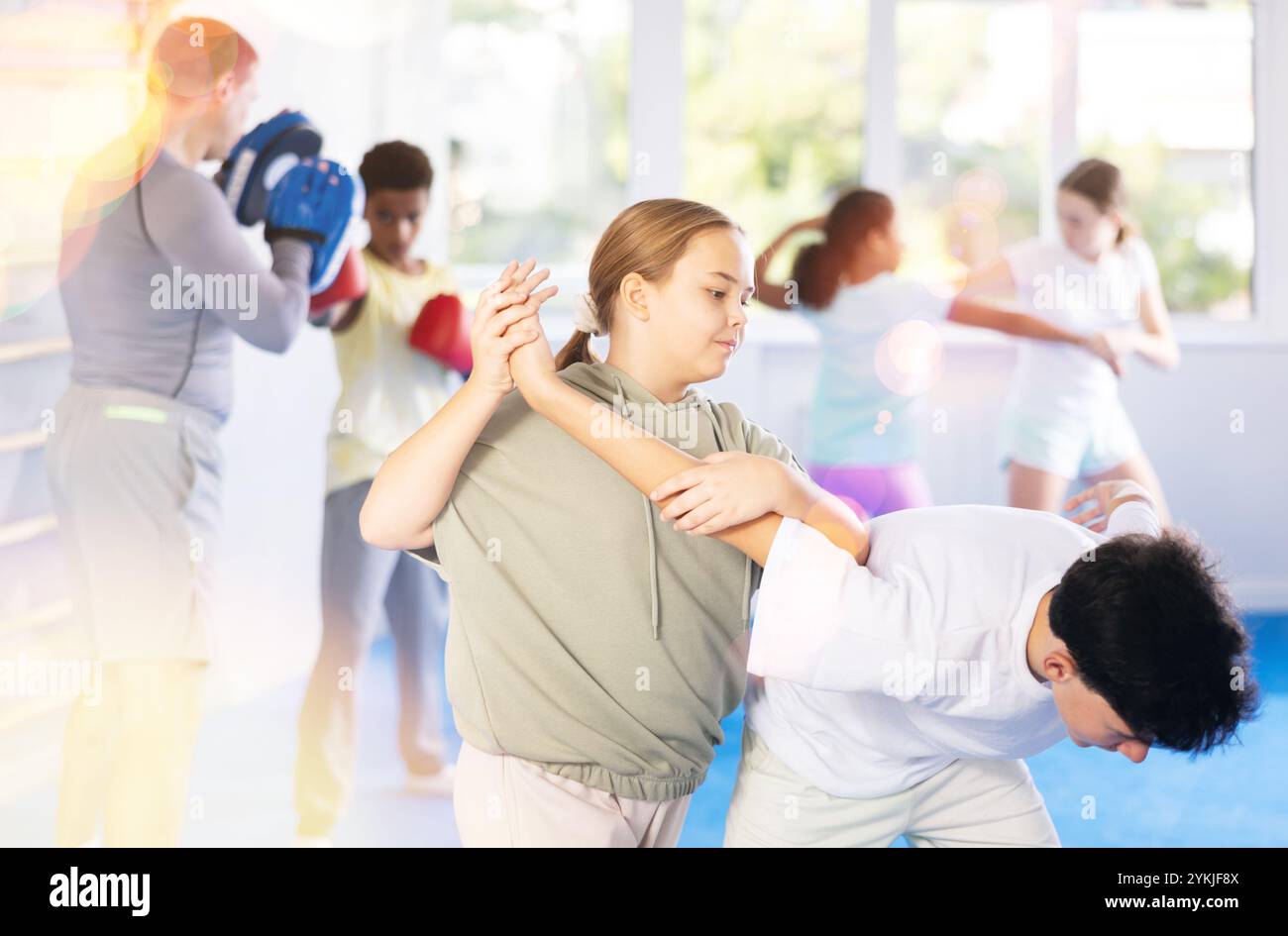Tween girl practicing painful armlock in training bout with boy during ...