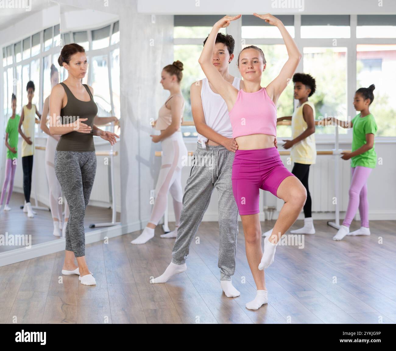 Teenage girl practicing ballet positions in pair with boy in dance ...