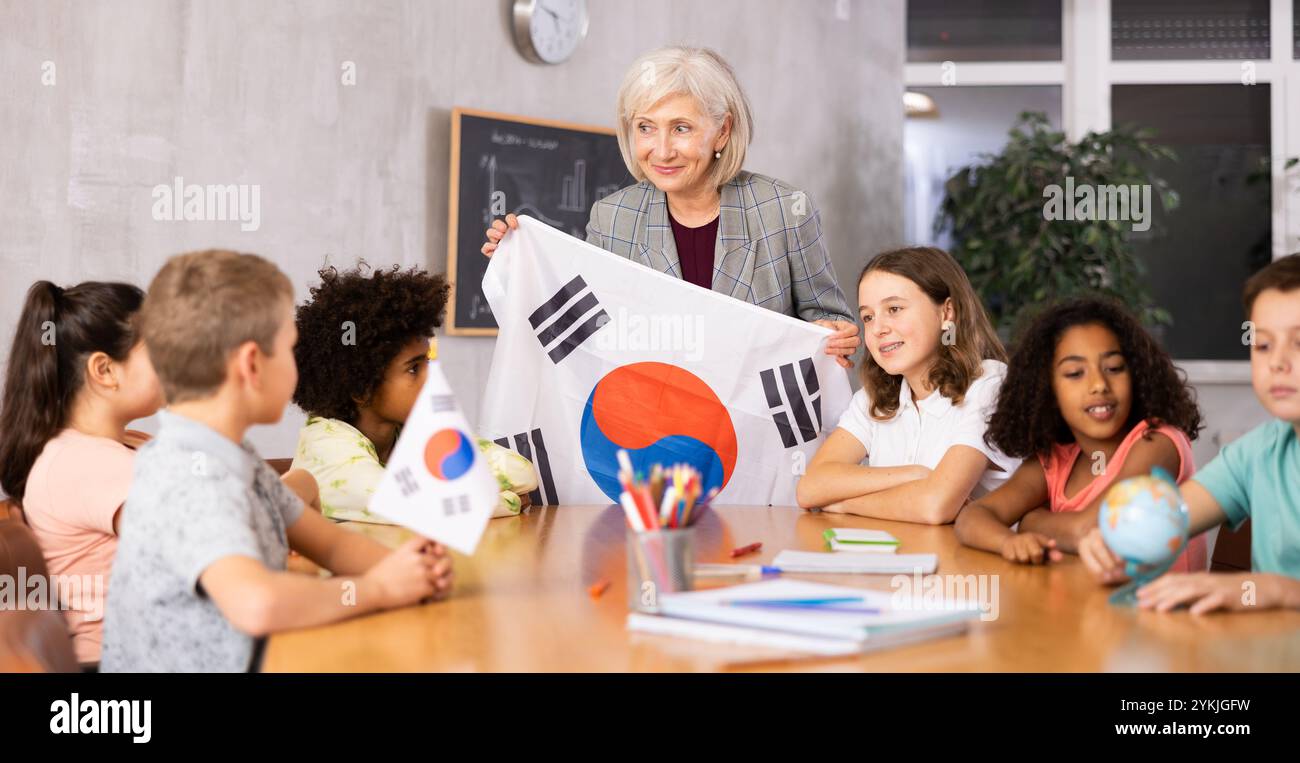 Female teacher showing south korean flag to kids in geography class ...