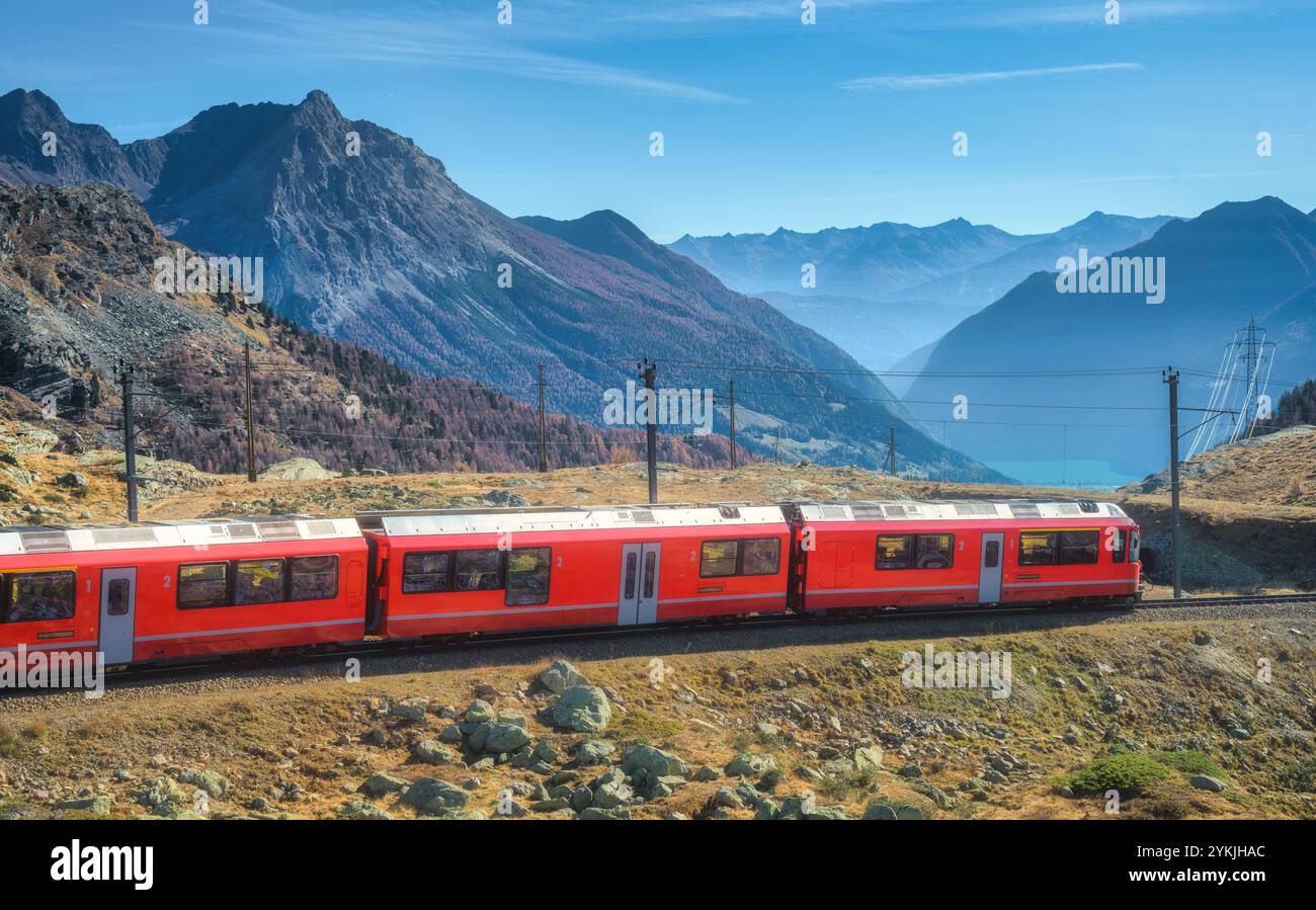 Red modern train is winding through the swiss alps on a sunny day Stock ...