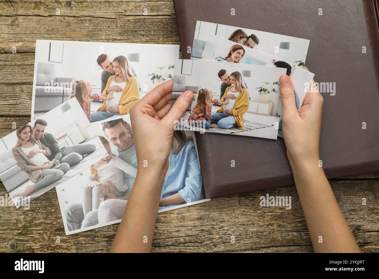 Woman with different photos and photo album at wooden table, top view ...