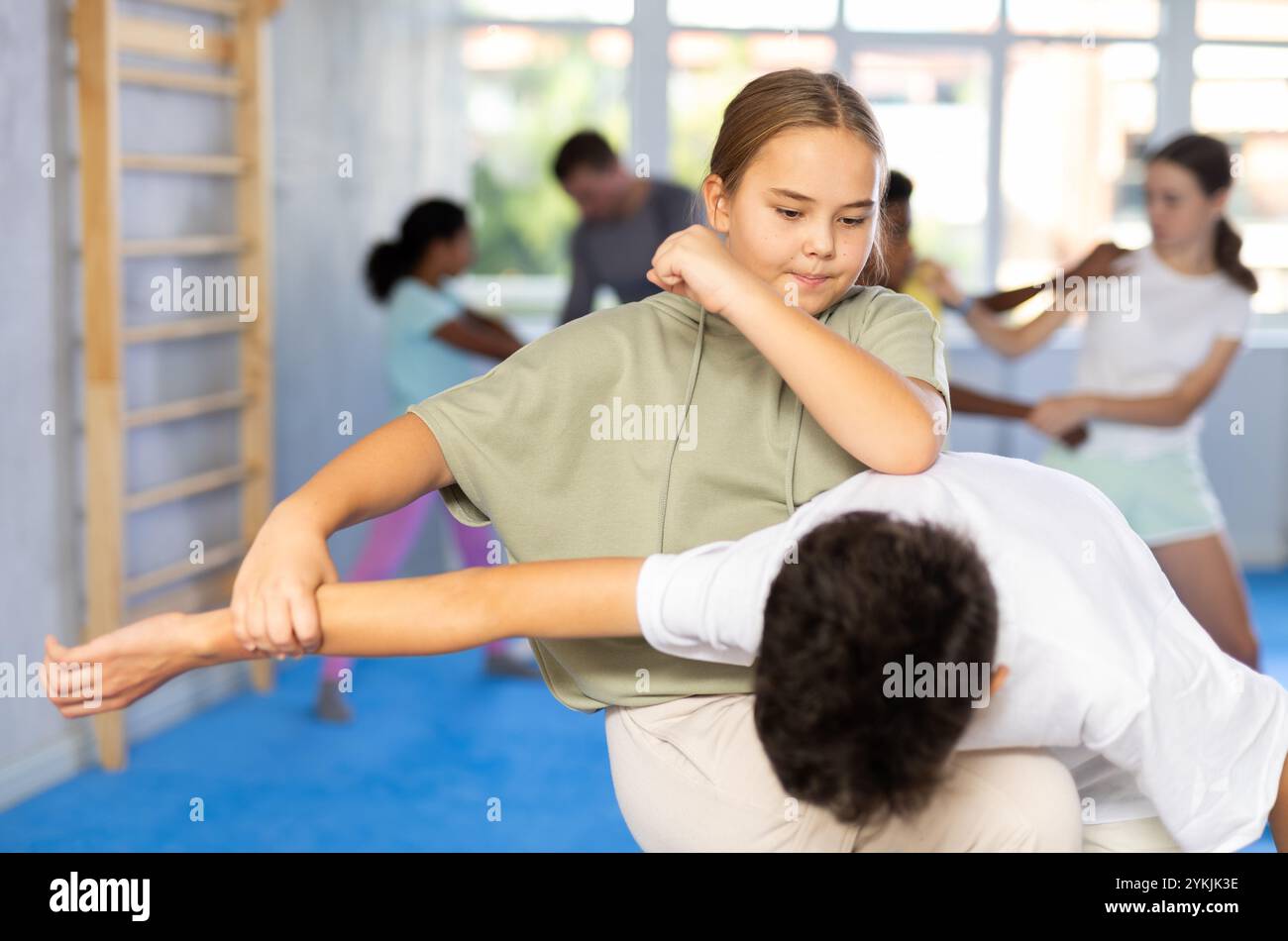 Girls and boys practicing in pair self defence movements with male ...