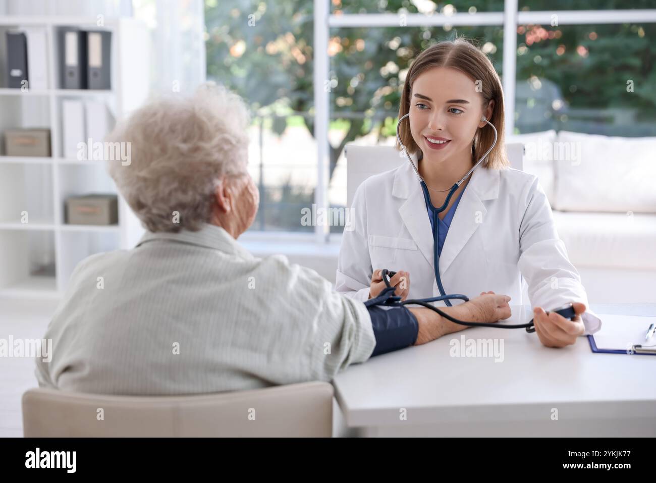 Doctor measuring patient's blood pressure at table in hospital Stock ...