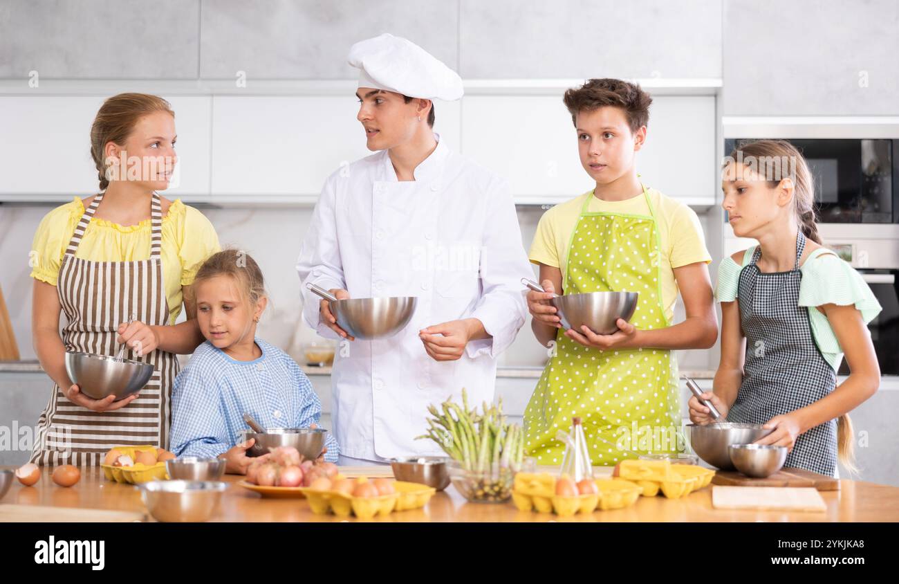 Young chef giving culinary classes to group of interested tweens Stock ...