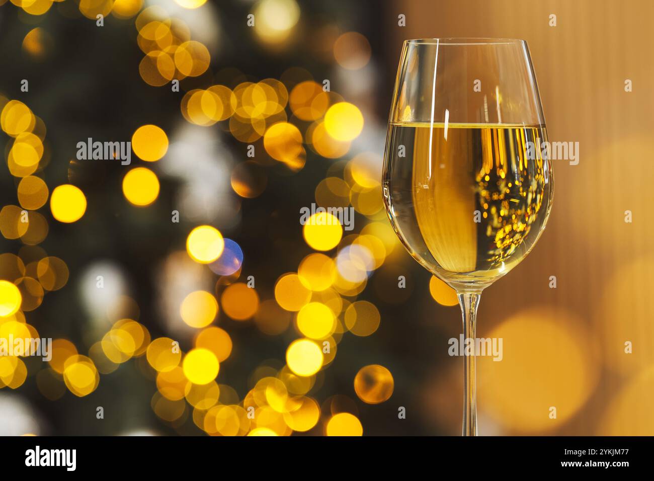 White wine in glass against blurred Christmas lights, space for text ...