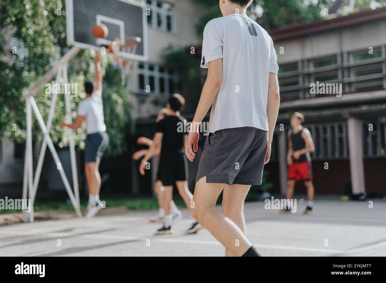 Friends playing basketball at a neighborhood court enjoying outdoor ...