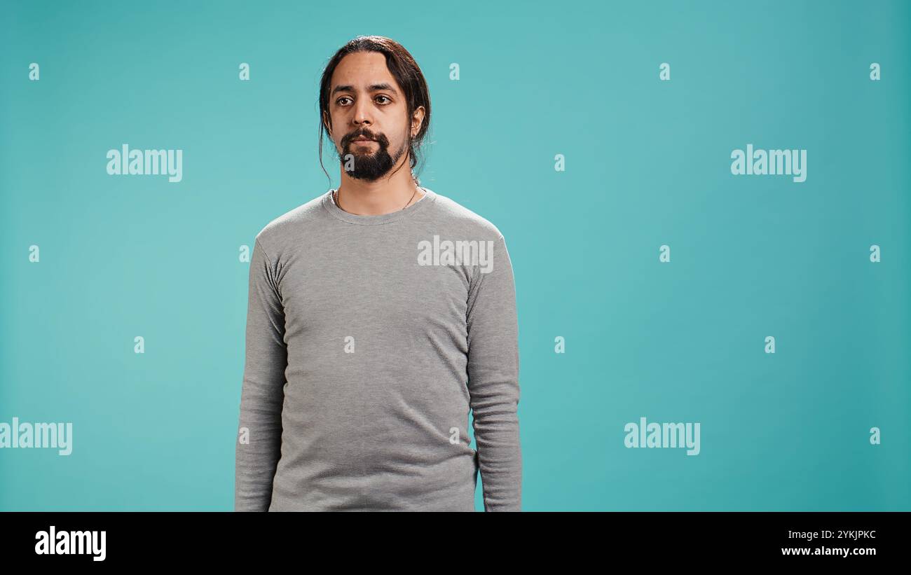 Portrait of serious Arab man standing isolated against blue studio background. Confident person ...