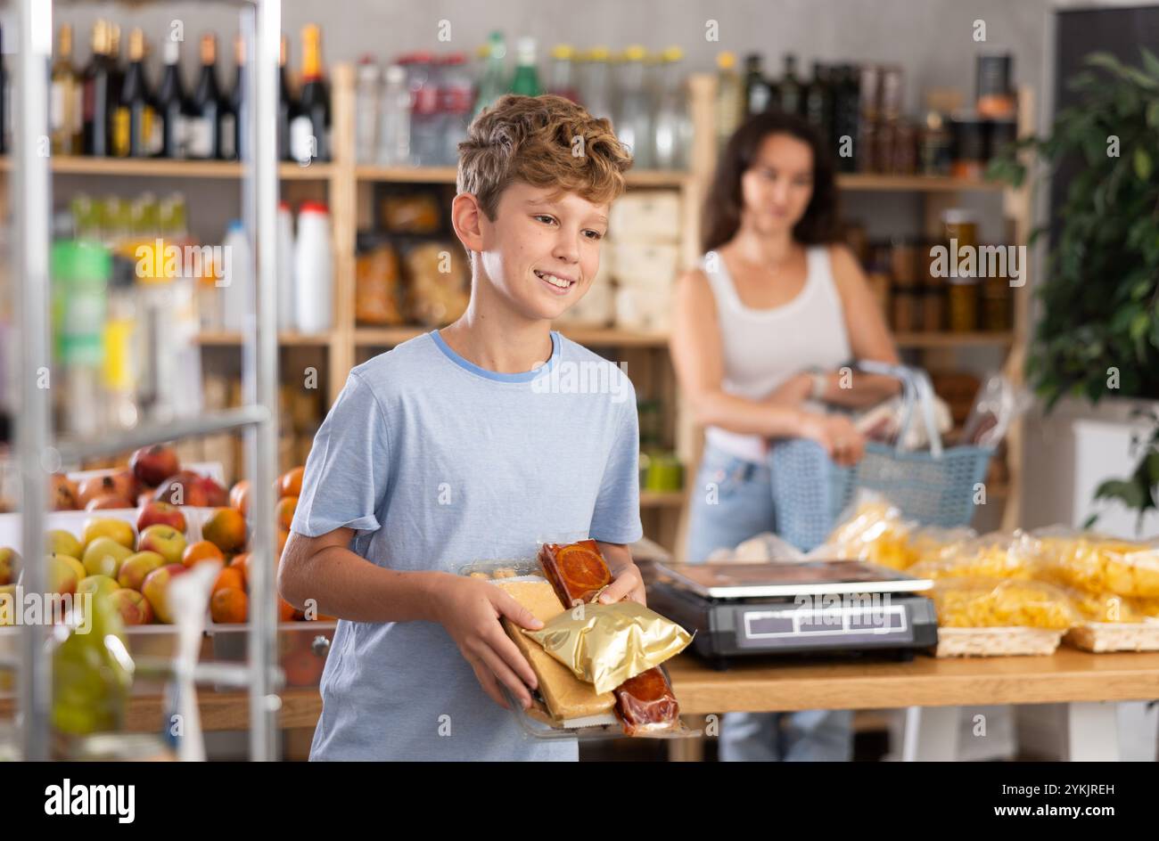 Joyful teenage boy choosing and buying different candies and sweets in ...